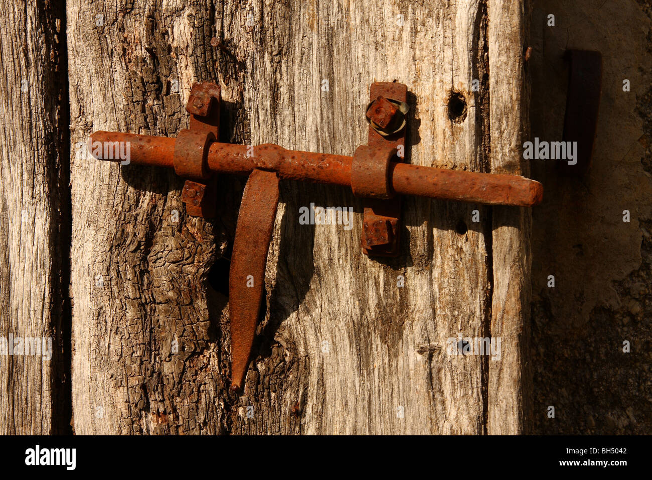 A typical rusty Limousin barn door bolt on a nicely textured wooden ...