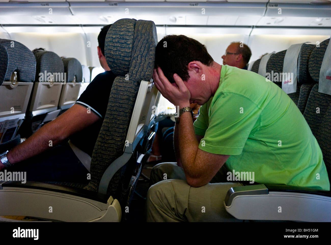 A man on board a plane with his head in his hands before the flight ...