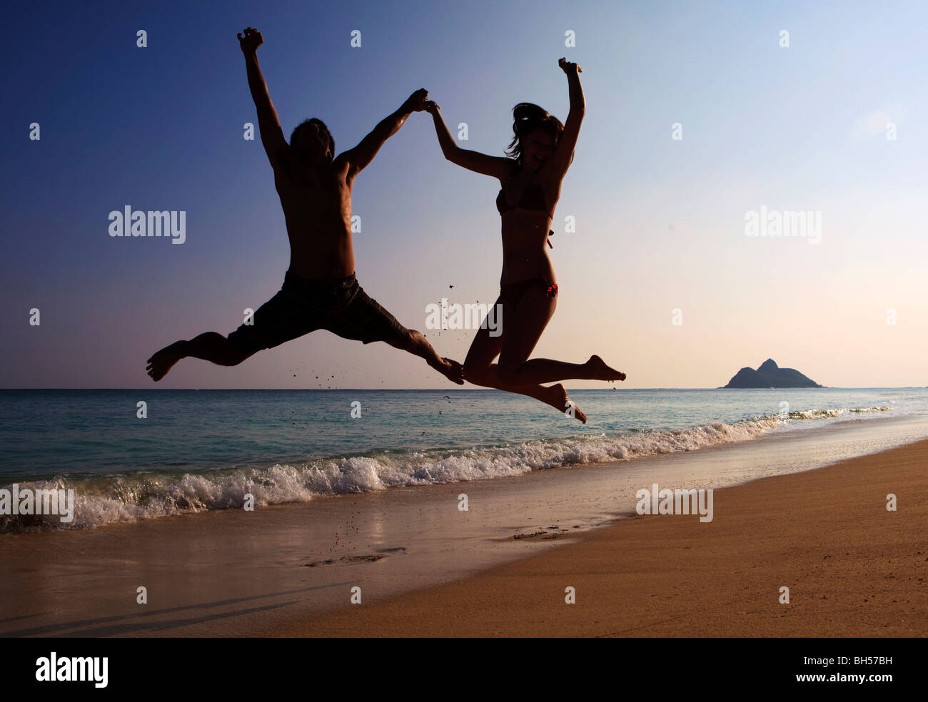silhouette of couple jumping in the air at a hawaii beach Stock Photo ...