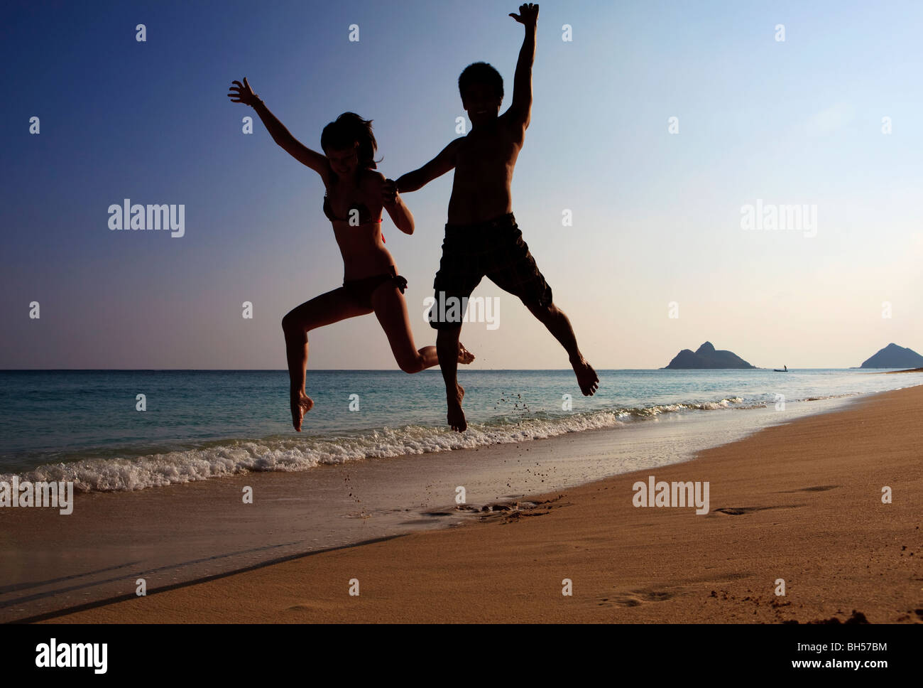 silhouette of couple jumping in the air at a hawaii beach Stock Photo ...