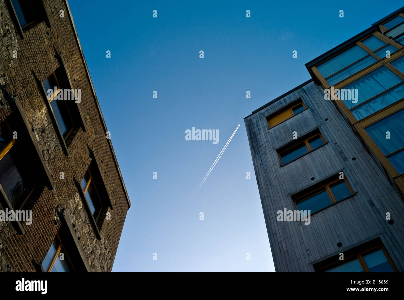 A jet plane flies over buildings high in the sky Stock Photo - Alamy