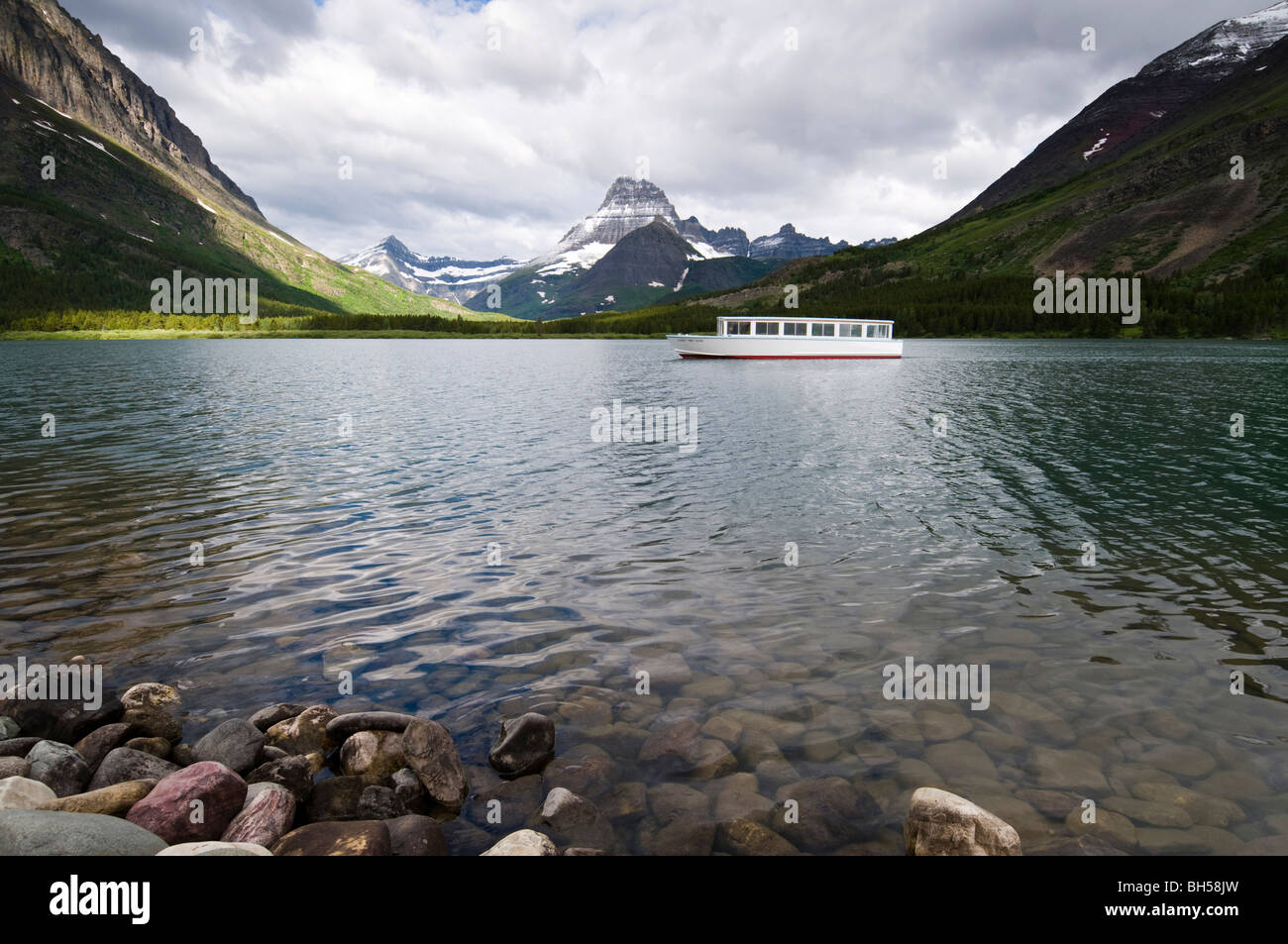 "Chief Two Guns" tour boat on Swiftcurrent Lake and mountains Stock ...