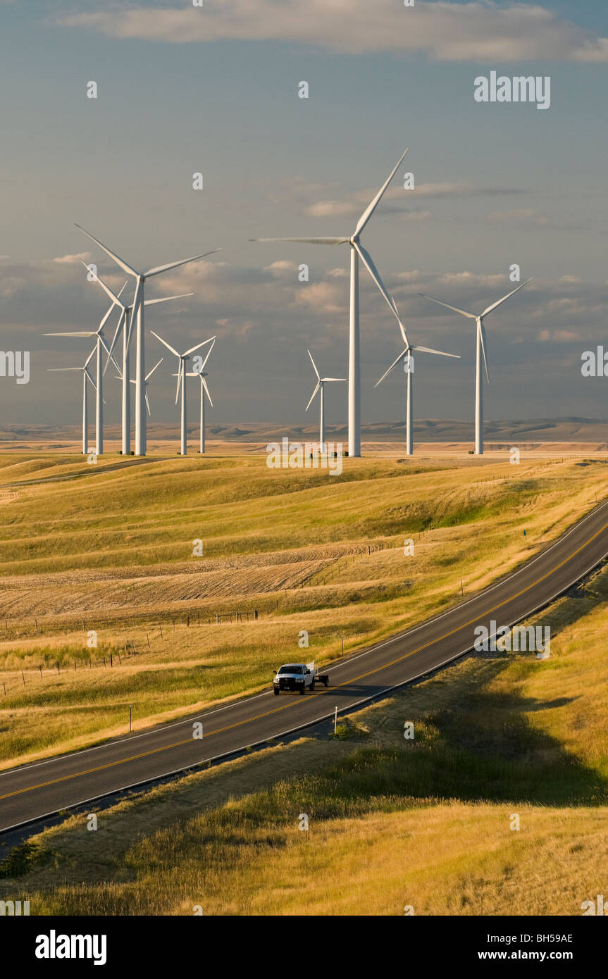 A pick-up truck on a lonely road is dwarfed by wind turbines at the ...