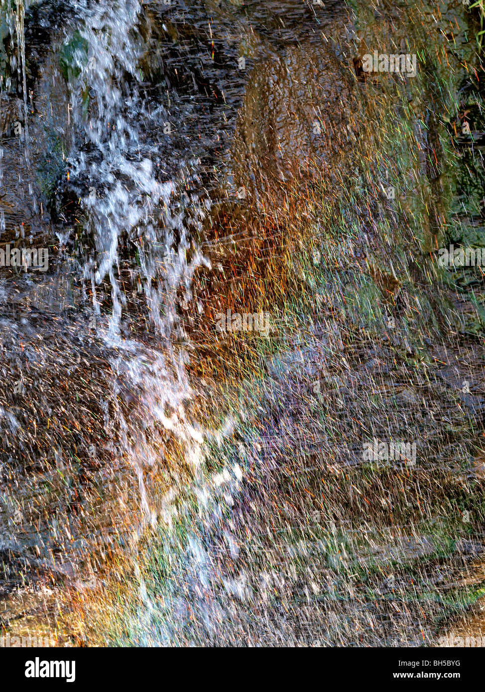 Sunlight through water droplets from a waterfall causing a rainbow ...