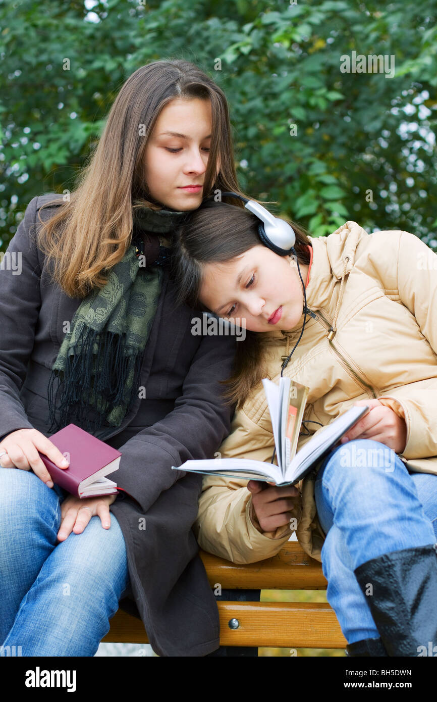 Two young teenage friends reading in the park Stock Photo - Alamy