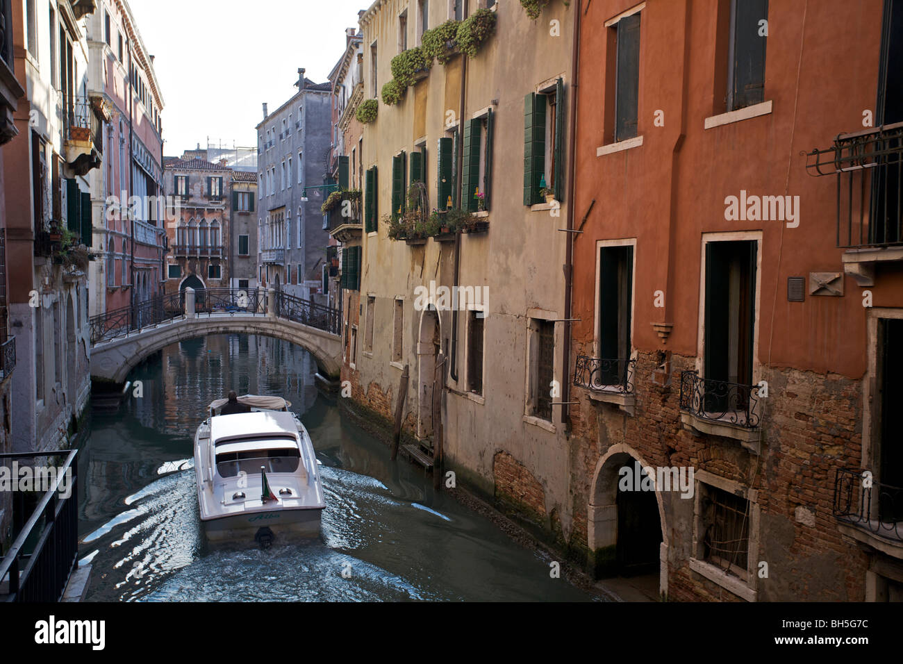 A Venetian water taxi goes under a footbridge in Venice, Italy, with ...