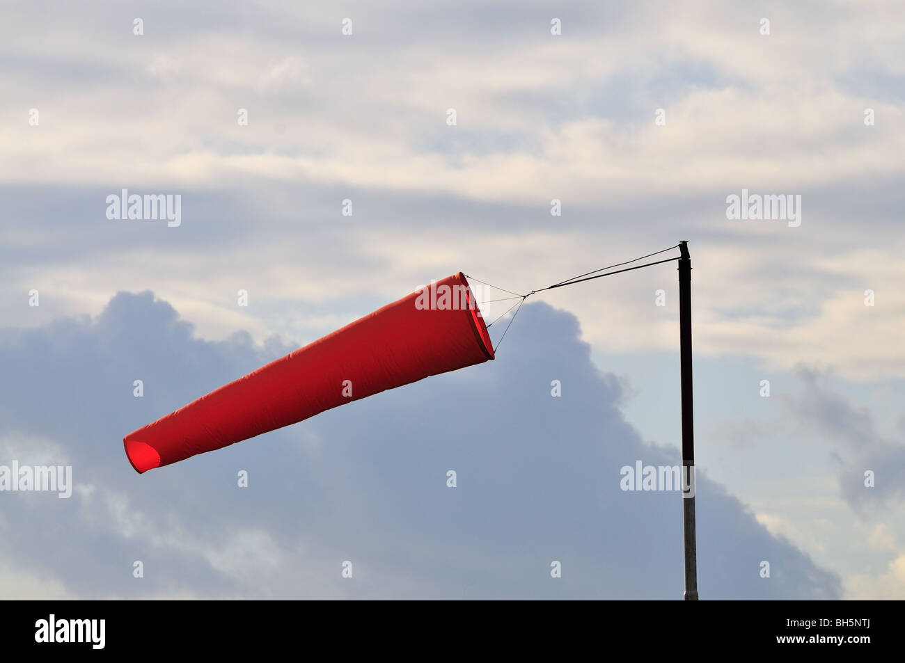 Red wind sock ,side view , fully inflated ,blue sky , high white cloud ...