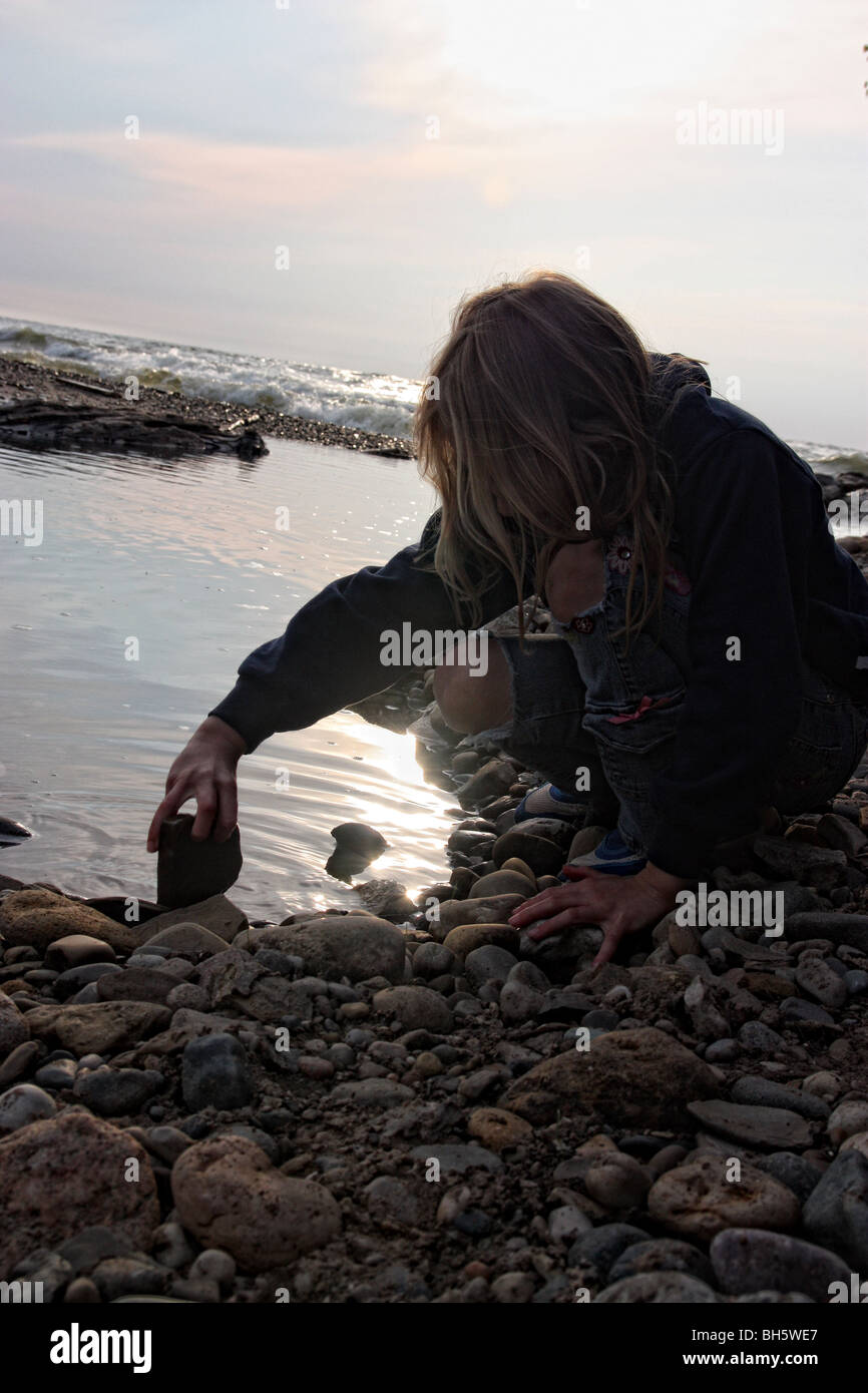 Girl playing with rocks by stream Stock Photo - Alamy