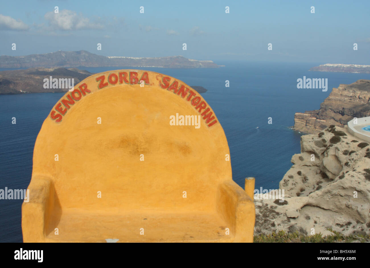 yellow bench with santorini sign with view of the caldera and the sea ...