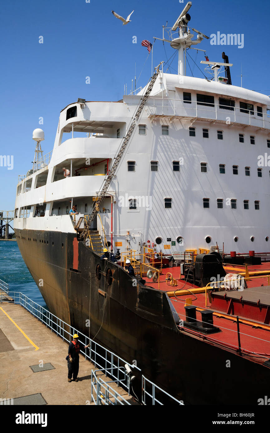 Dock side workers taking the lines of a lake freighter passing through ...
