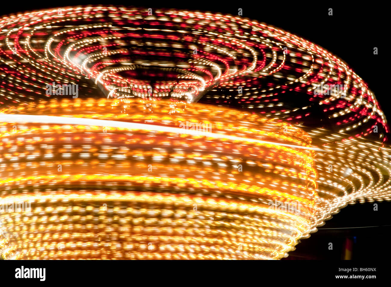 Swirling lights of carnival rides at night Stock Photo - Alamy