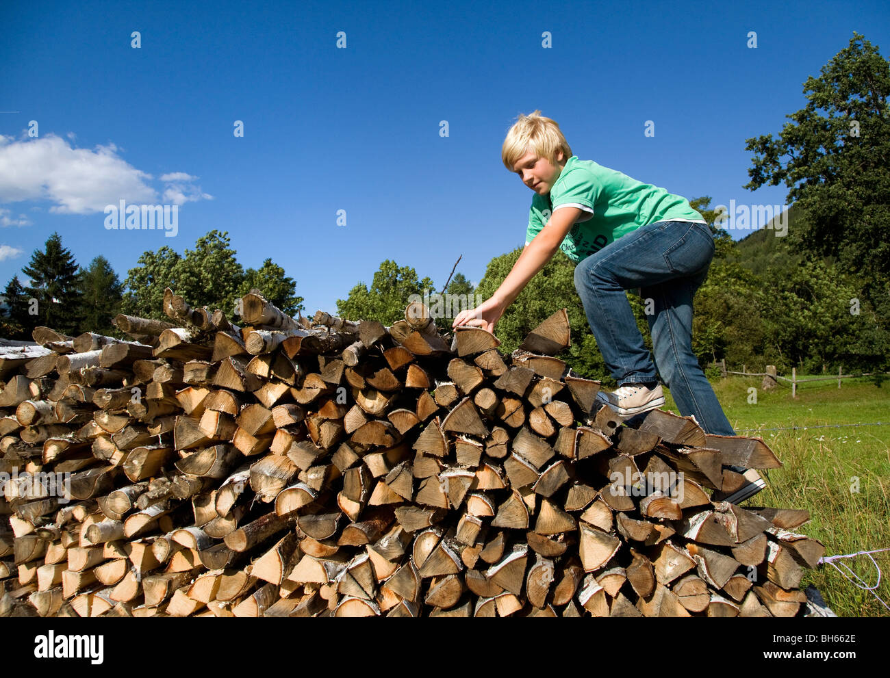 boy climbing stack of wood Stock Photo - Alamy