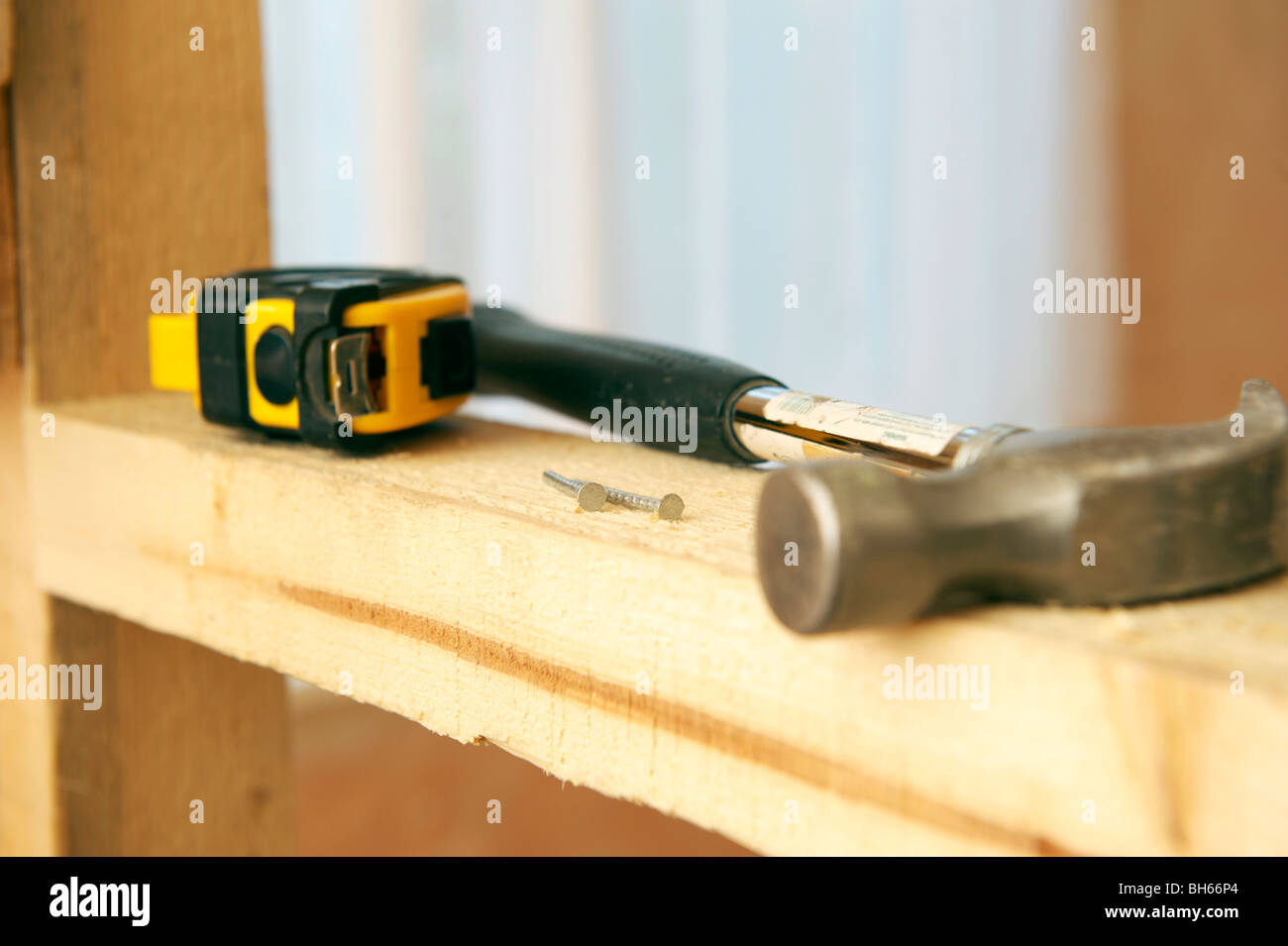Hammer and tape measure lying on wood from a stud wall in renovated ...