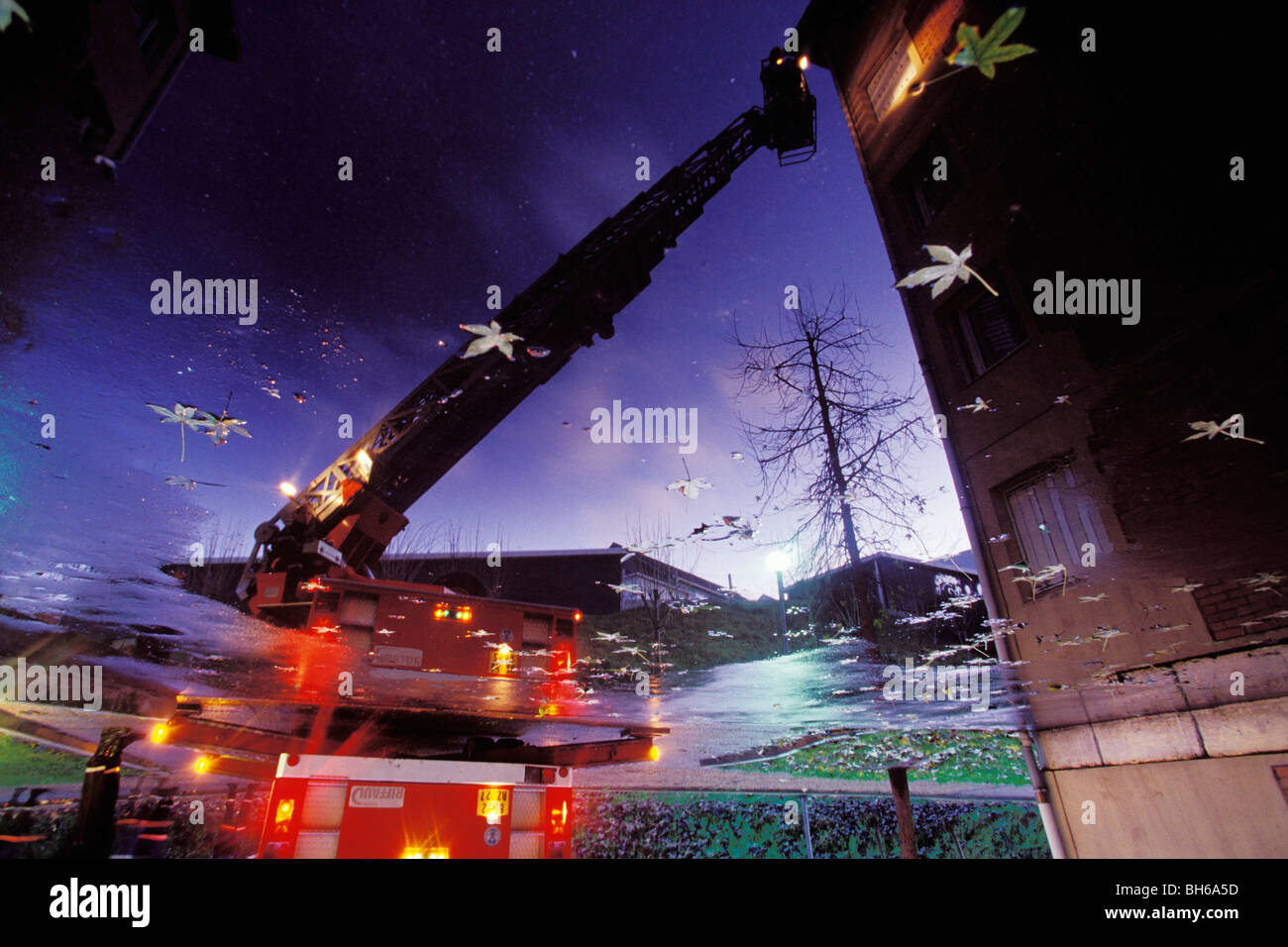 REFLECTION OF THE FIREFIGHTERS' AERIAL TURNTABLE LADDER IN A PUDDLE OF ...