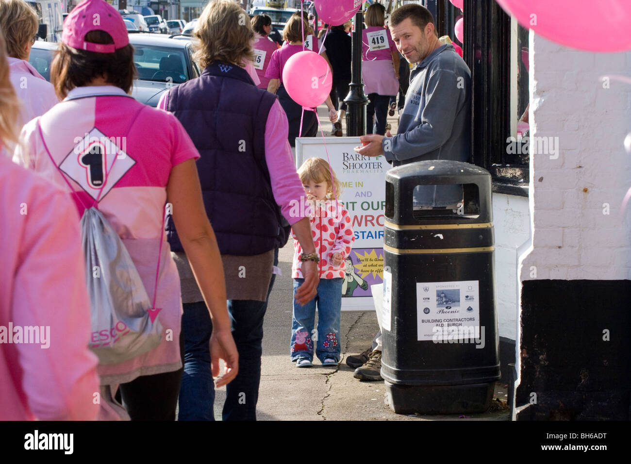 A little girl and her dad watch women in pink pass Stock Photo - Alamy