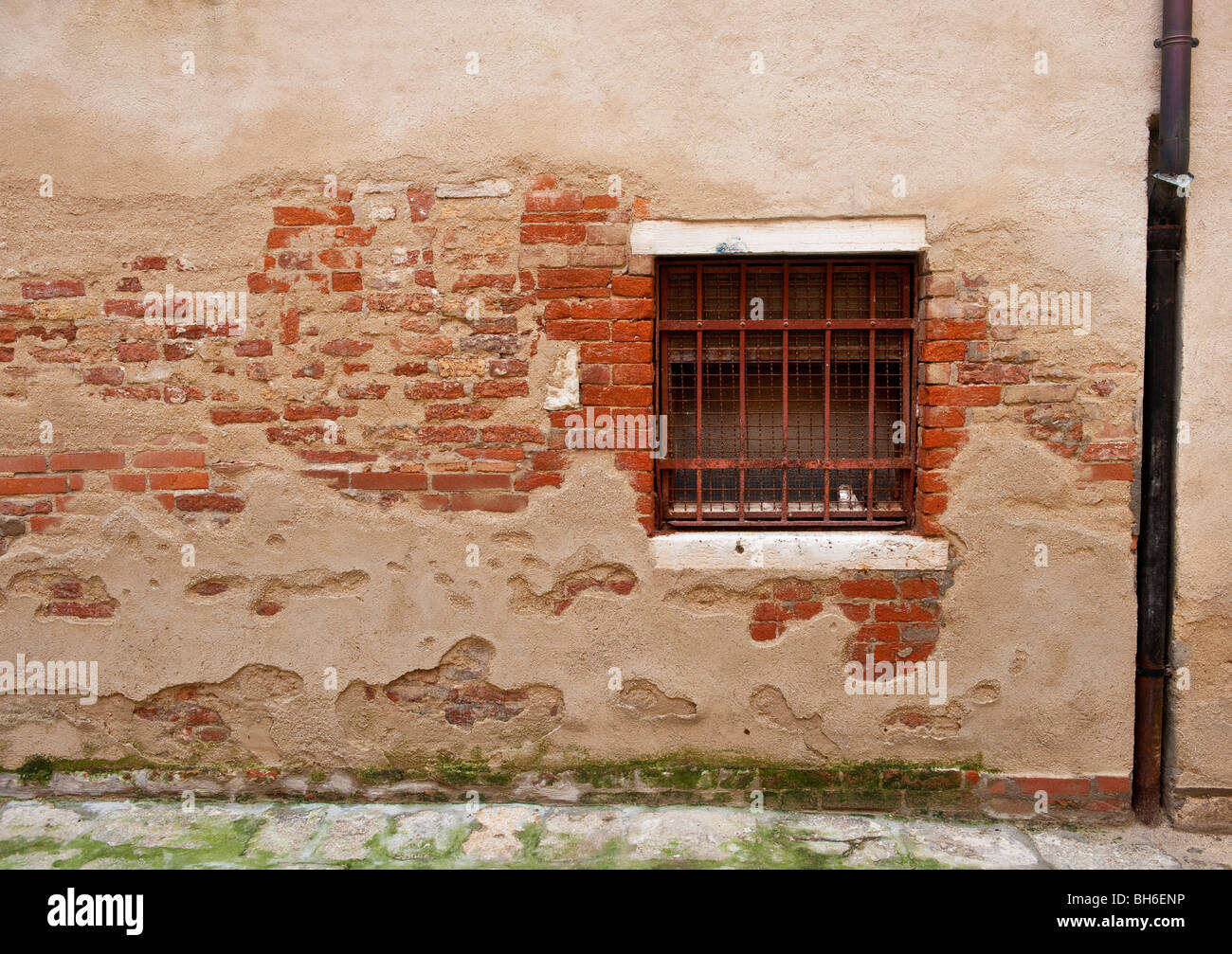 Window with bars and stucco wall with exposed brick, Venice, Italy ...