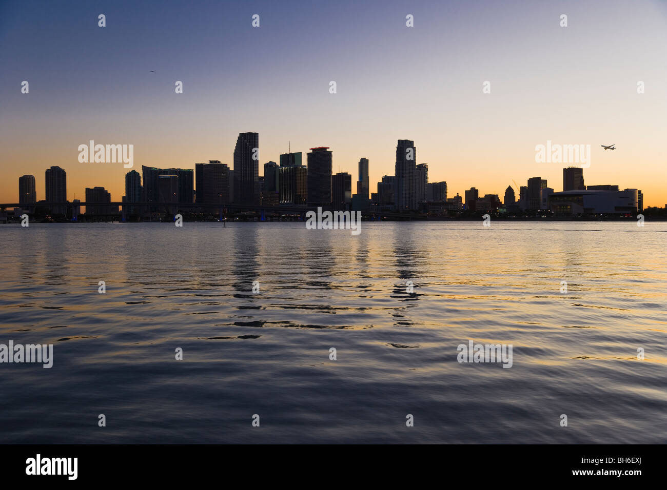 Passenger aircraft flying over Miami skyline at sunset, Florida, USA ...