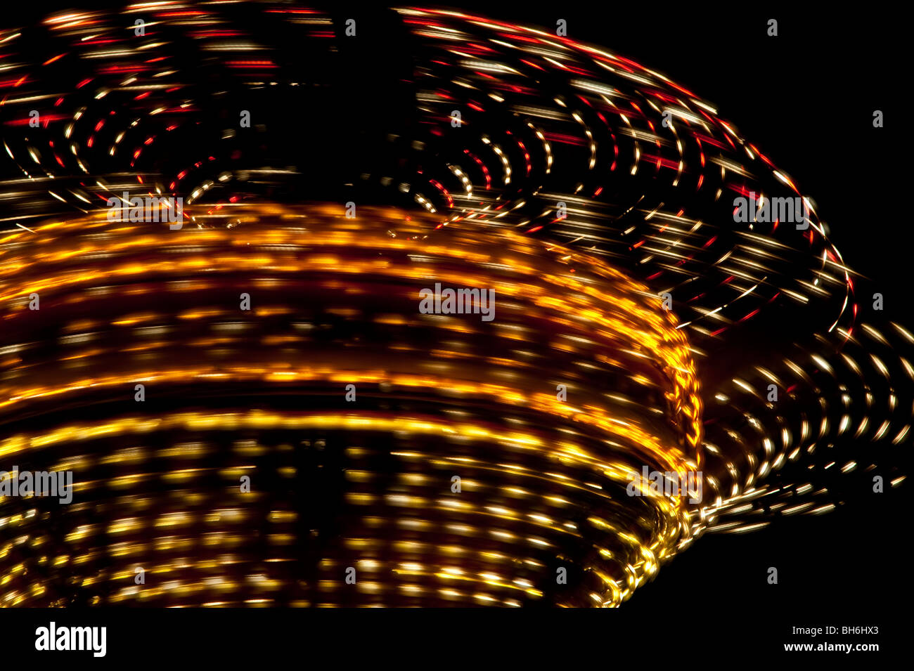 Swirling lights of carnival rides at night Stock Photo - Alamy