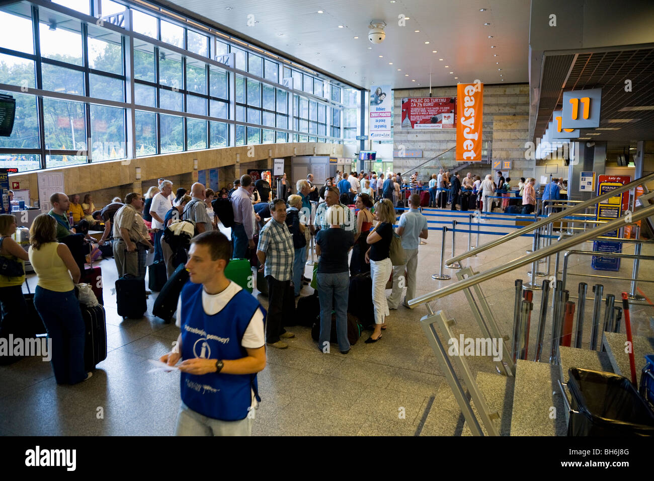 Departing passengers queue in departures check-in hall for checkin at ...