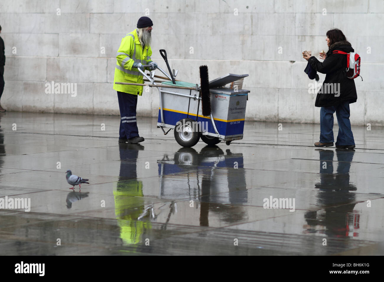 A street cleaner pushes his cart in Trafalgar Square, London, along a ...