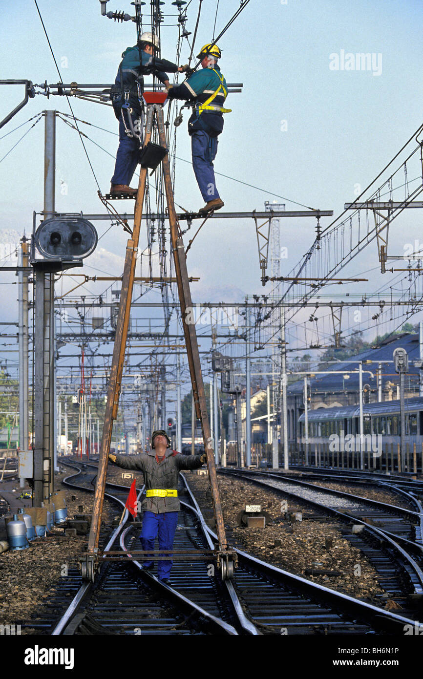 TWO RAILWAY WORKERS AT THE TOP OF A LADDER PREPARING A CATENARY ...