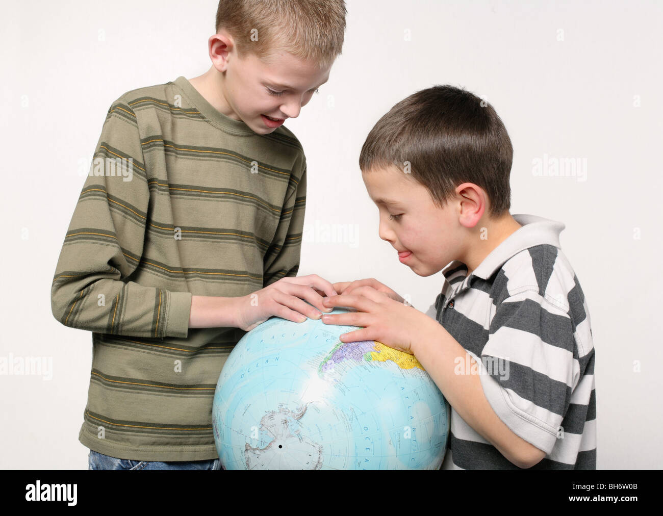 two elementary school age boys looking closely at a world globe on ...
