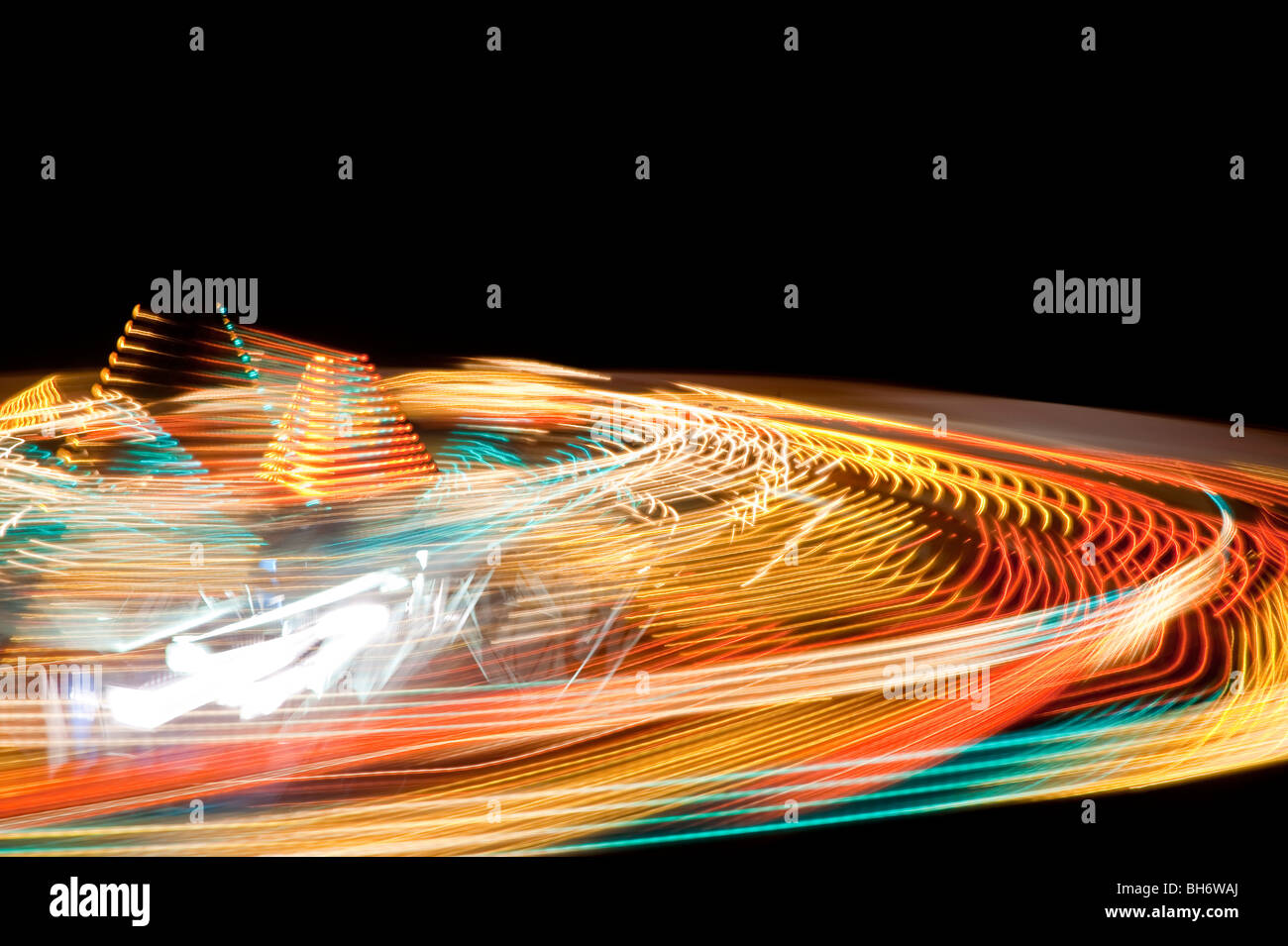 Swirling lights of carnival rides at night Stock Photo - Alamy