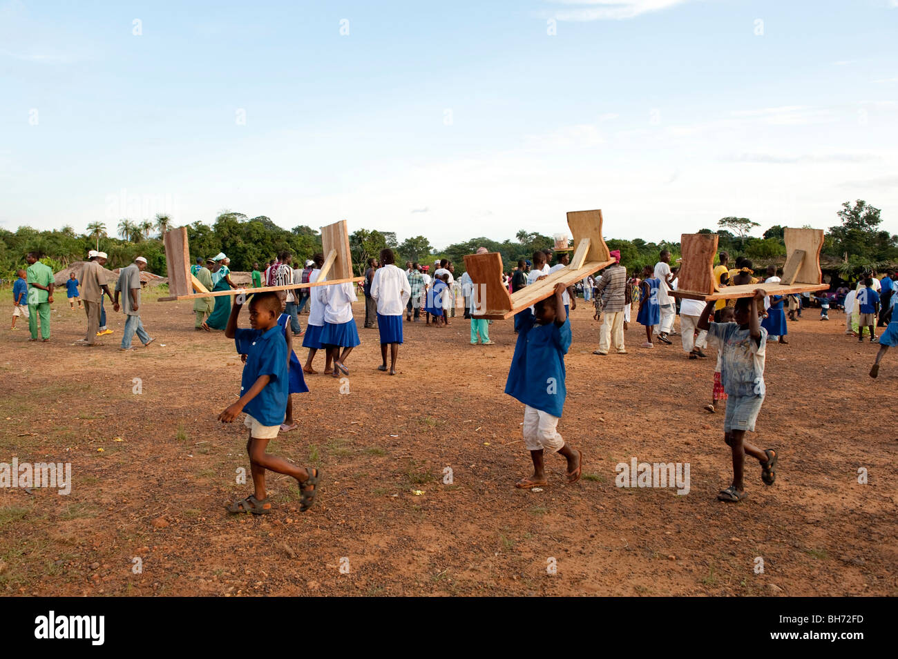 Boys carrying benches ngo town sierra leone Stock Photo - Alamy