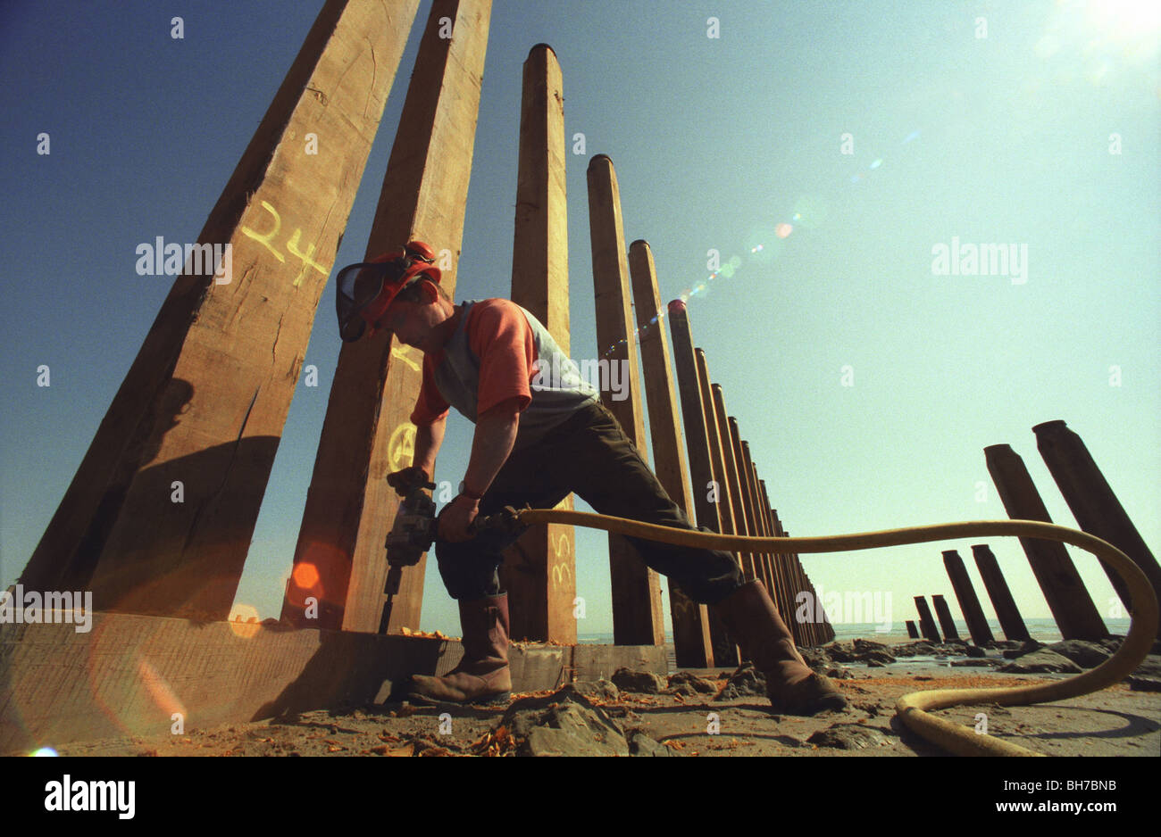 A workman fixing the supports for a new sea defence groyne on the beach ...