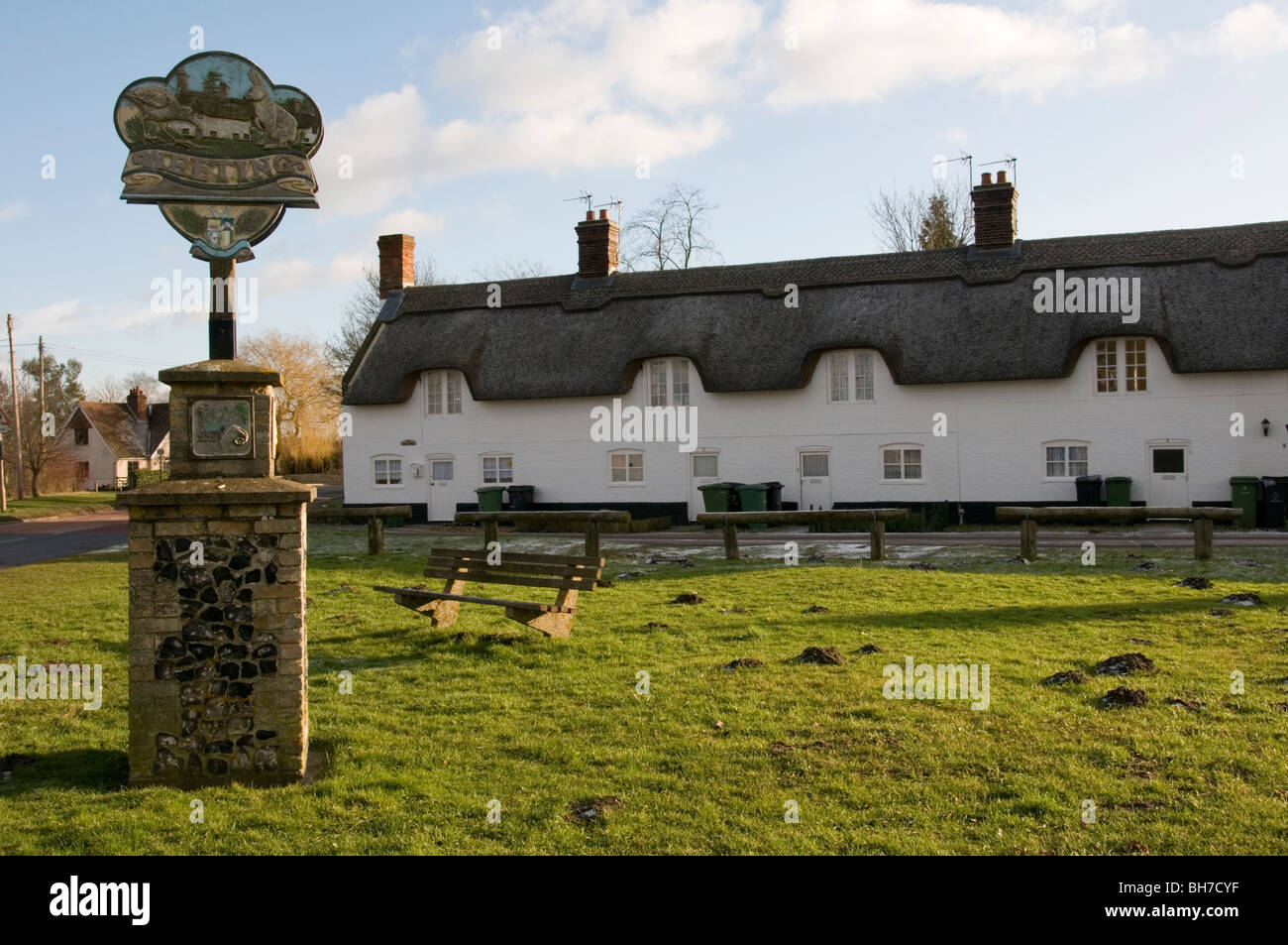 The village sign of Weeting in Norfolk with 'The Row' cottages behind ...