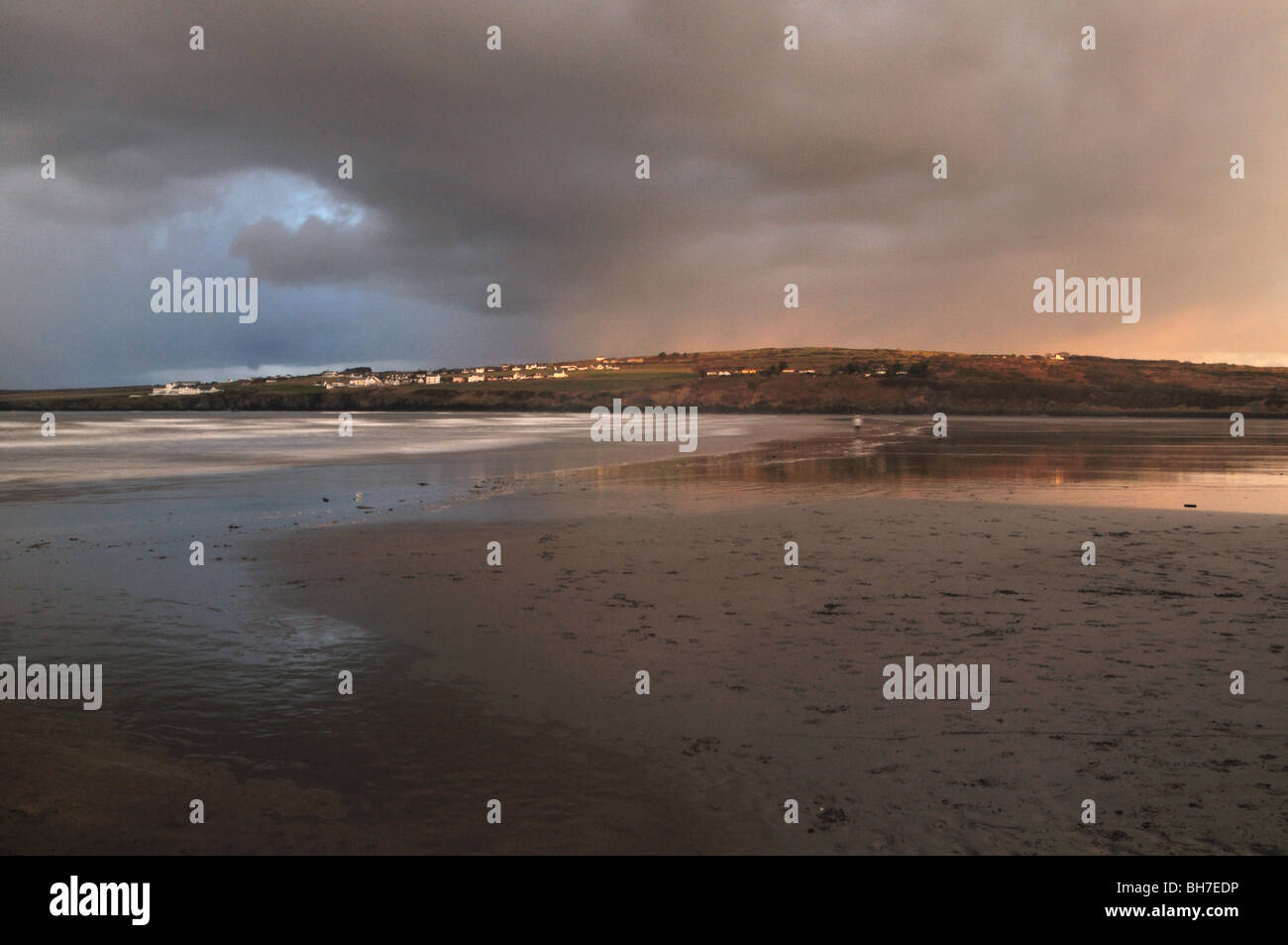 Reflections of pink snow clouds in sand, Poppit Sands beach, St ...