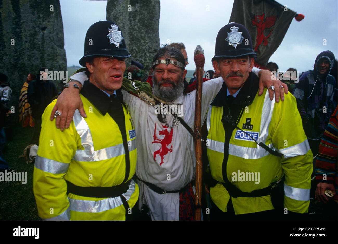 A pagan worshipper hangs his arms over the shoulders of two police ...