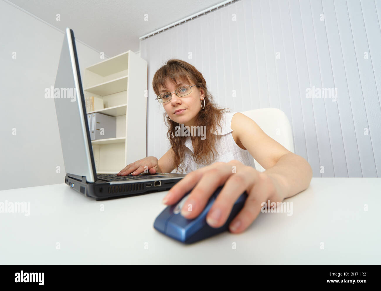 Young woman working with laptop photographed comic foreshortening Stock ...
