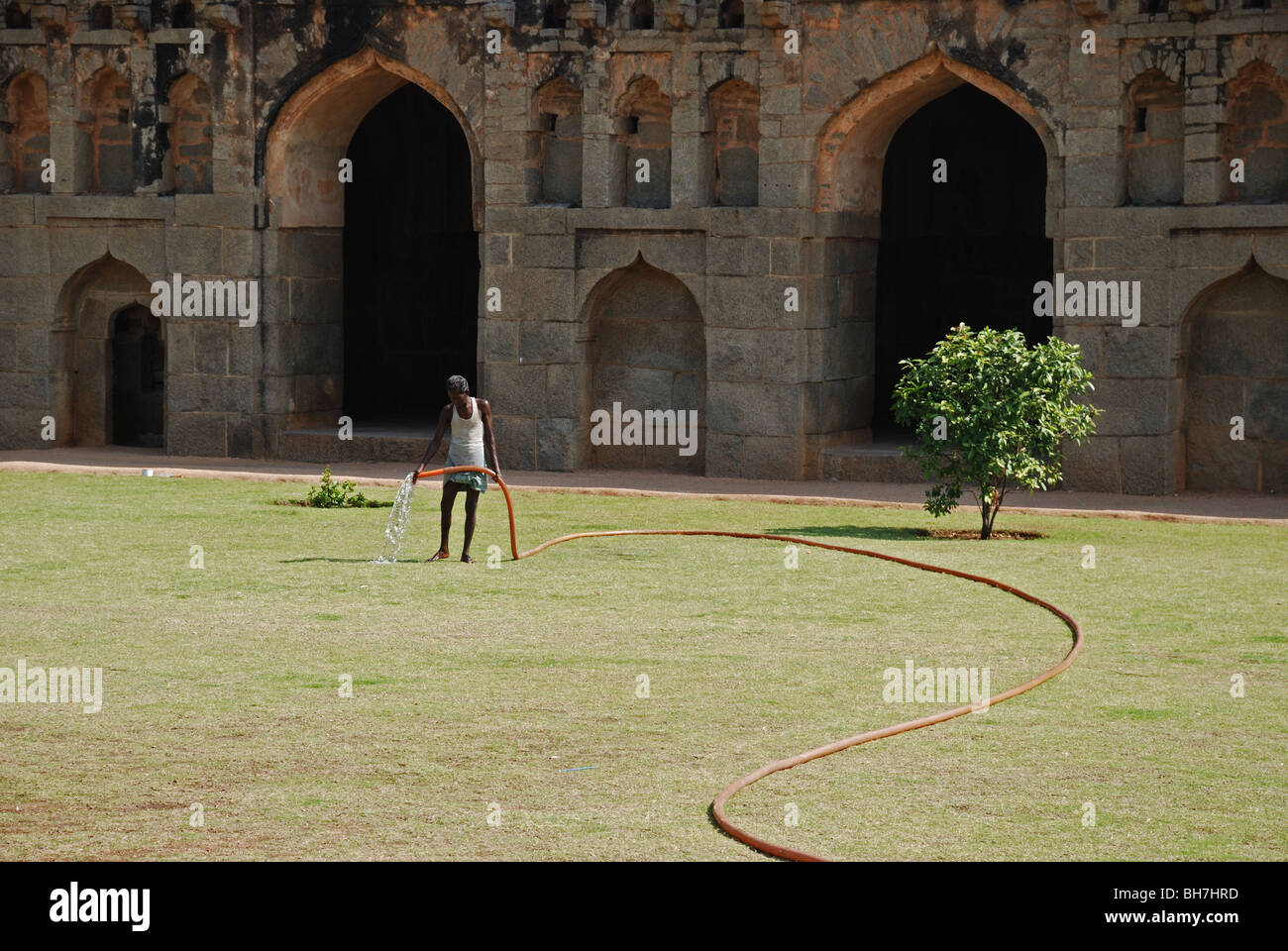 Man watering the grass at the Elephant Stables, Hampi, India Stock ...