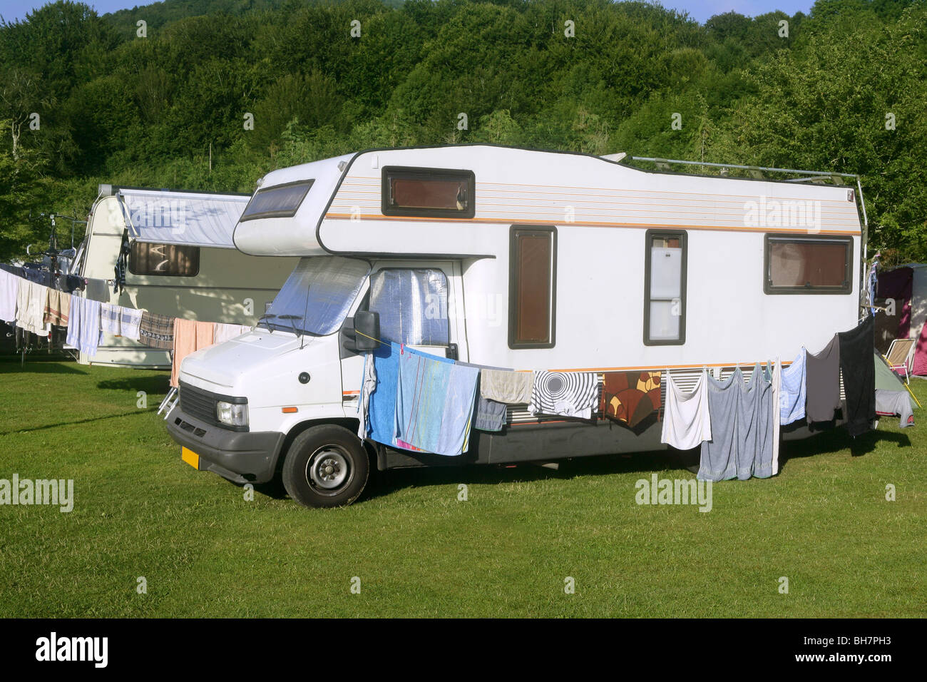 Caravan van in the green meadow forest camping Stock Photo - Alamy