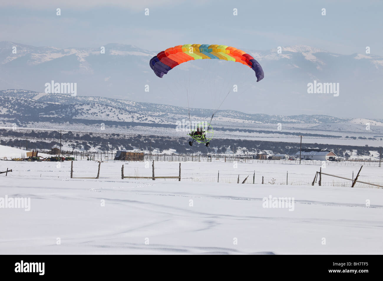 Powered parachute flying across ice and snow covered rural farms in ...