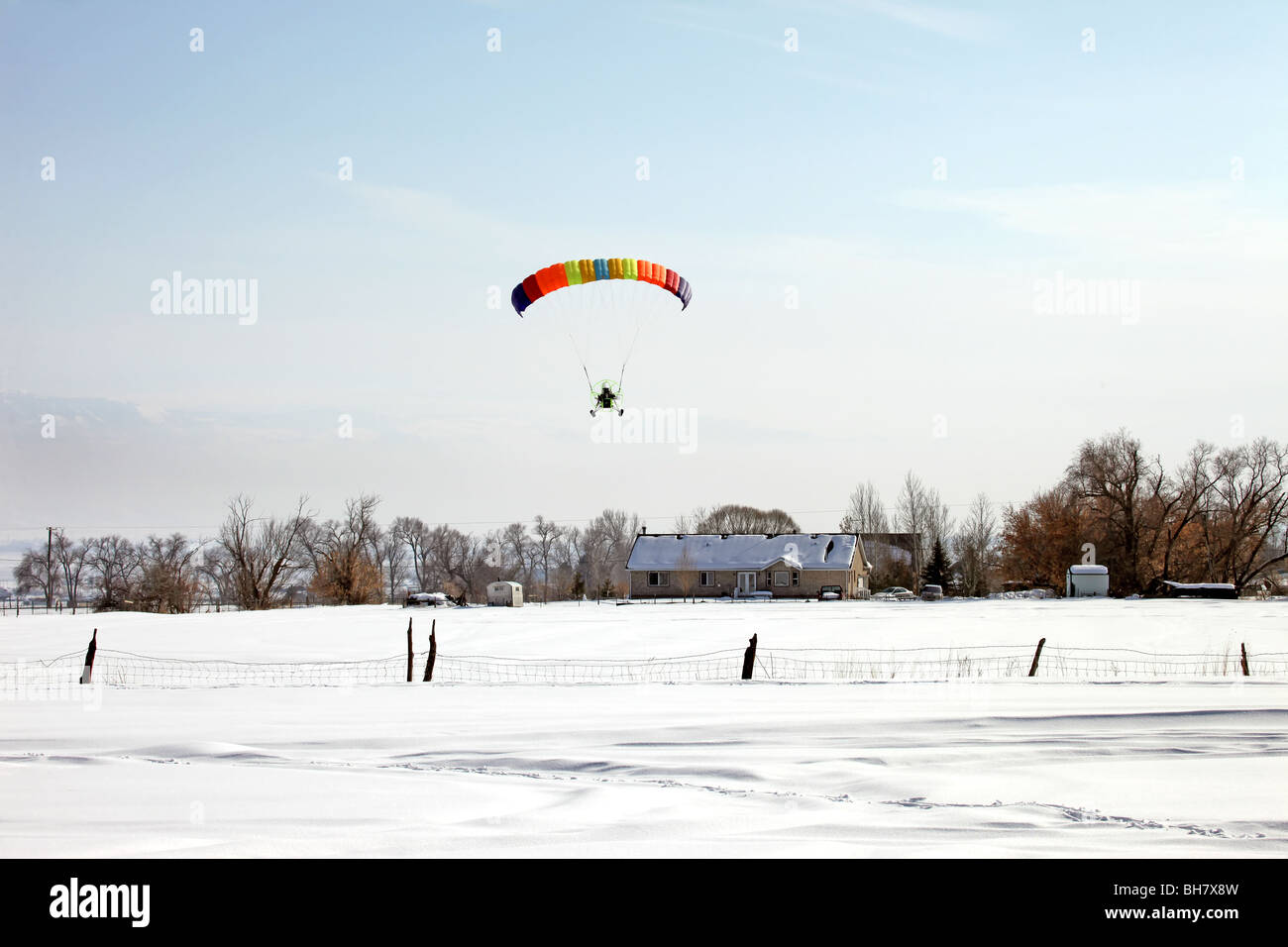 Powered parachute flying across ice and snow covered rural farms in ...