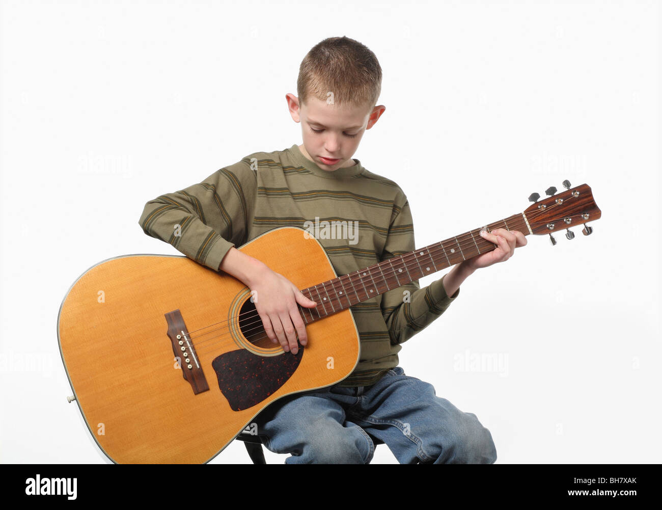 elementary age child sitting and playing a large acoustic guitar Stock ...