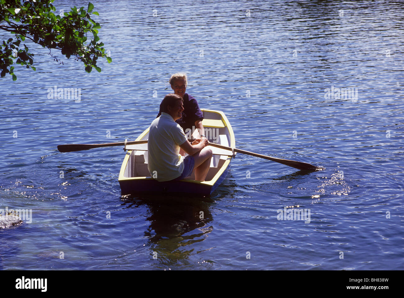 couple in a row boat where the man traditionally is rowing and the ...