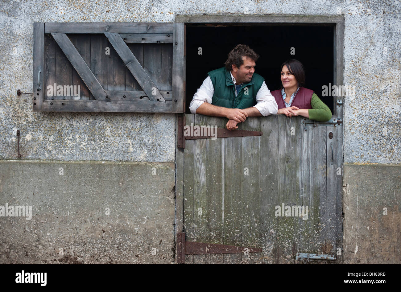 couple leaning on stable gate Stock Photo - Alamy