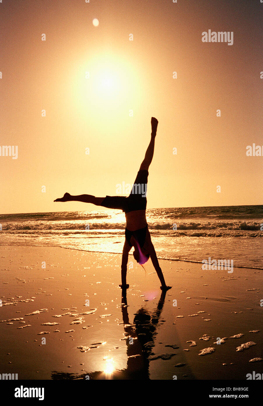 A woman doing a cartwheel on a beach at sunset Stock Photo - Alamy