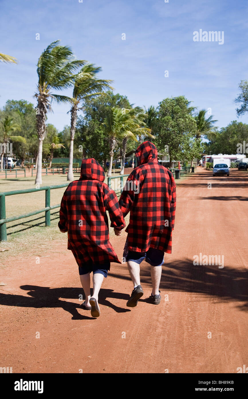 Rear view of two people dressed in red checked jackets walking down a ...