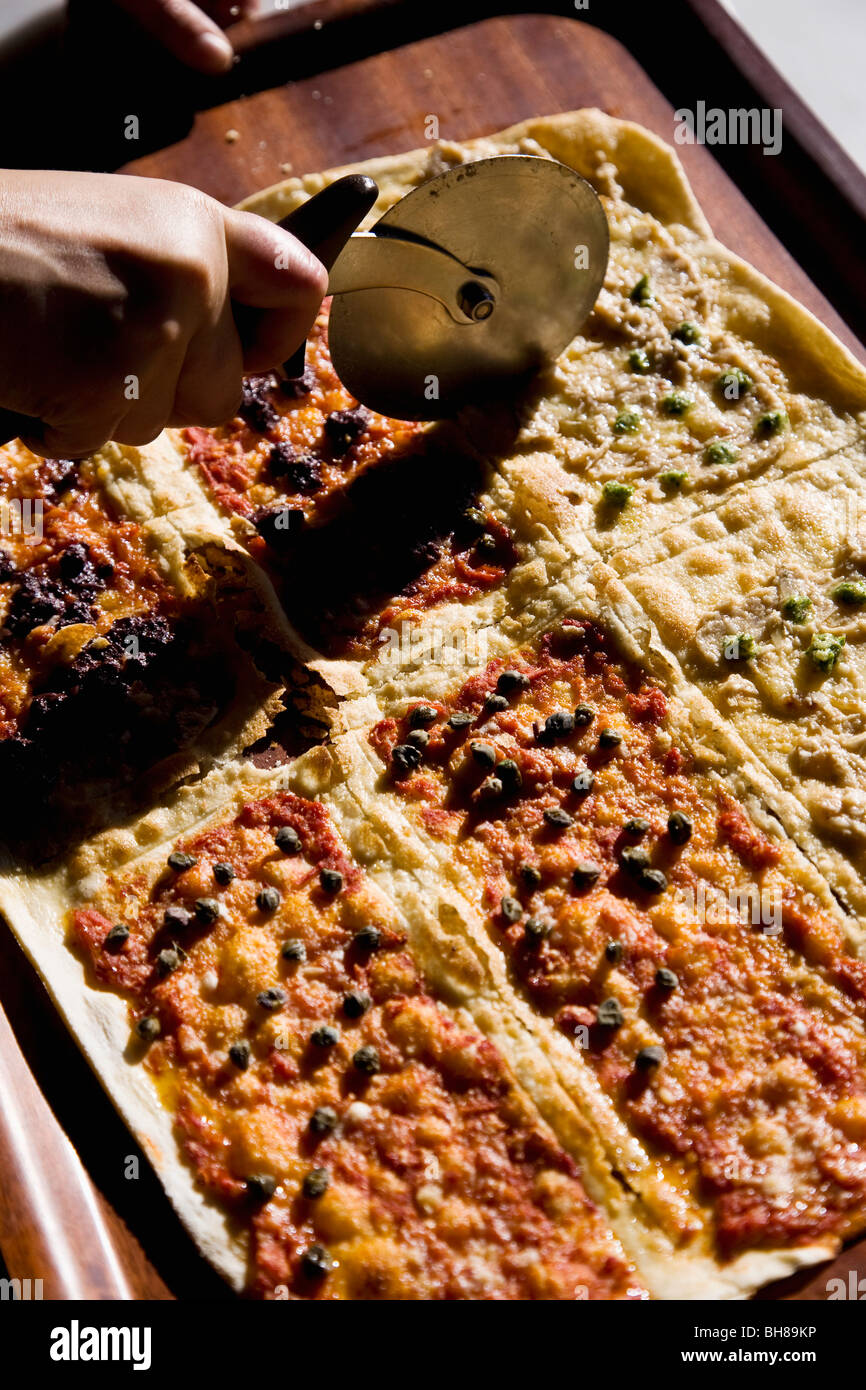 Detail of a pizza being cut Stock Photo - Alamy