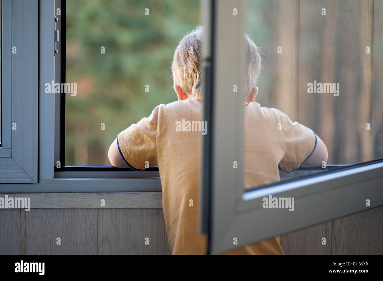 Rear view of a boy looking out a window Stock Photo - Alamy