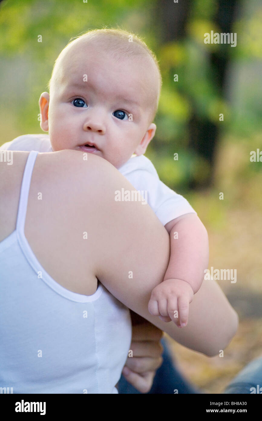 A baby boy being carried by his mother, over the shoulder view Stock ...