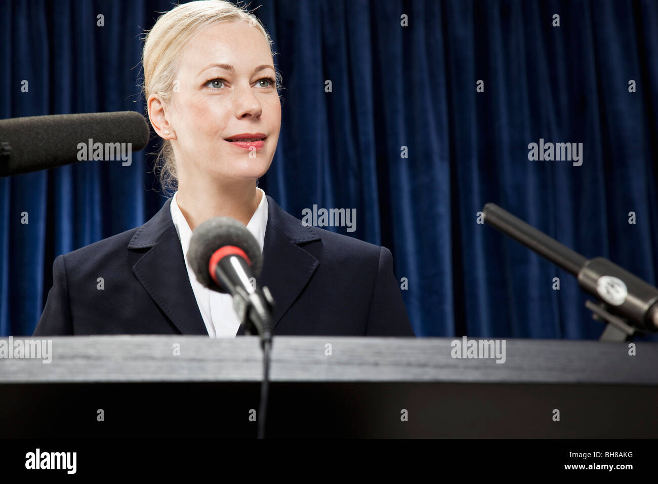 A woman in a suit at a lectern Stock Photo - Alamy