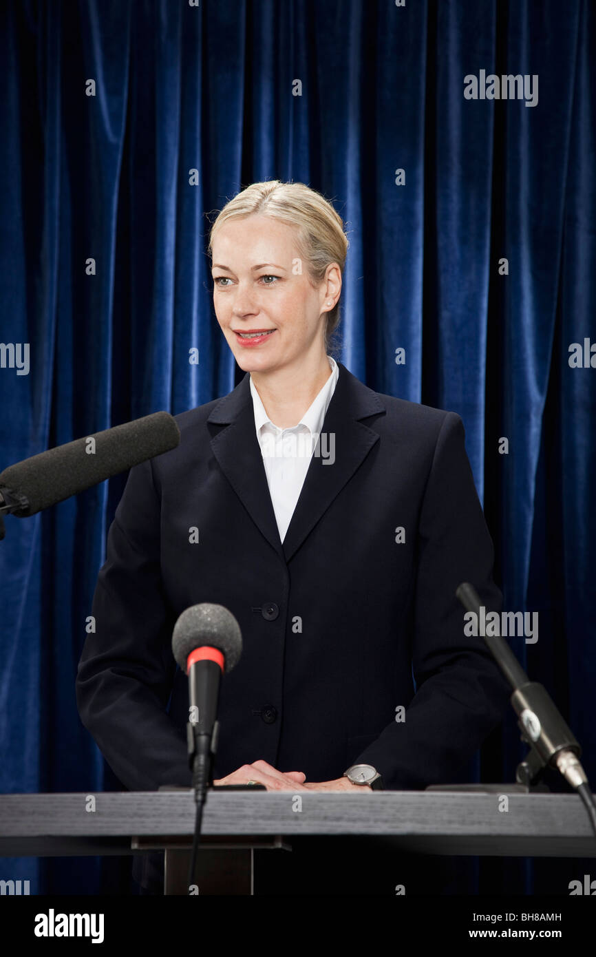 A woman in a suit standing at a lectern Stock Photo - Alamy
