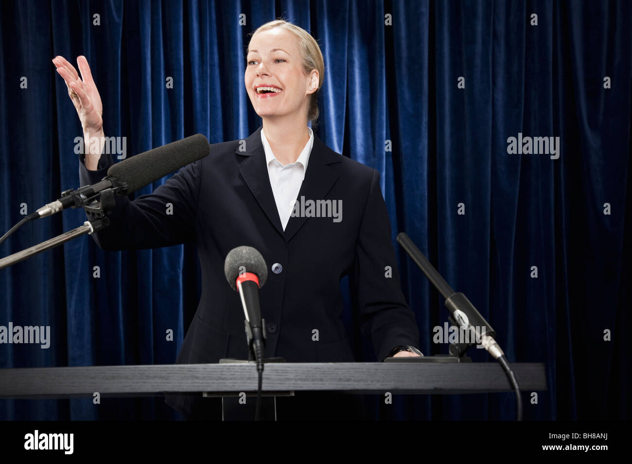 A woman in a suit gesturing at a lectern Stock Photo - Alamy