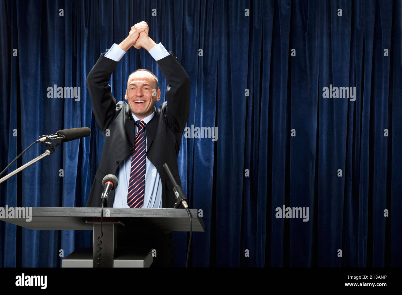 A man in a suit cheering at a lectern Stock Photo - Alamy