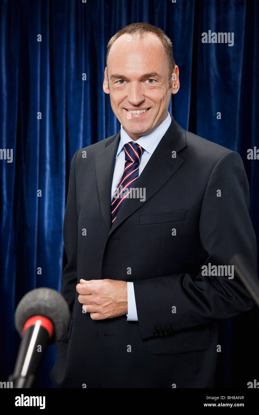 Portrait of a man in a suit behind a microphone Stock Photo - Alamy